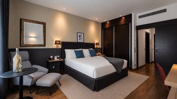 Quarto de hotel moderno com uma cama grande, mesas de cabeceira, uma escrivaninha e uma cadeira.