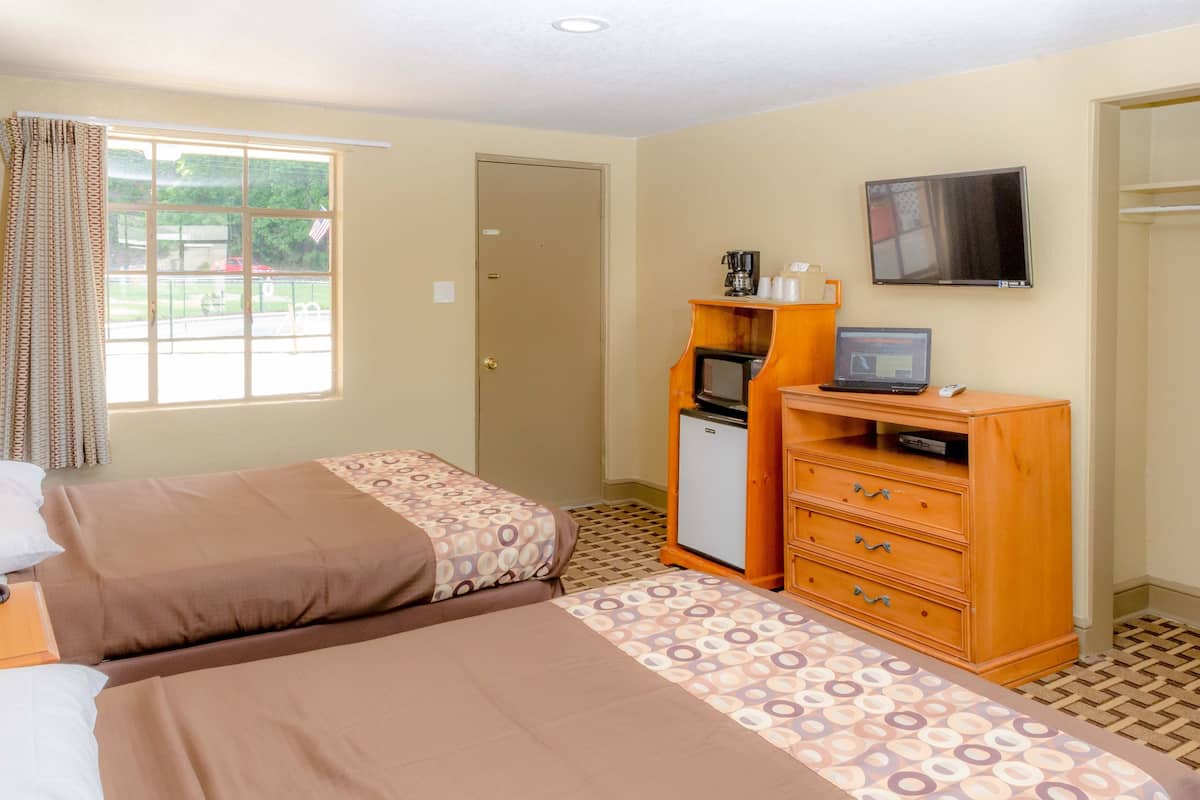 Quarto de hotel com duas camas, televisão, cafeteira e um pequeno frigorífico.