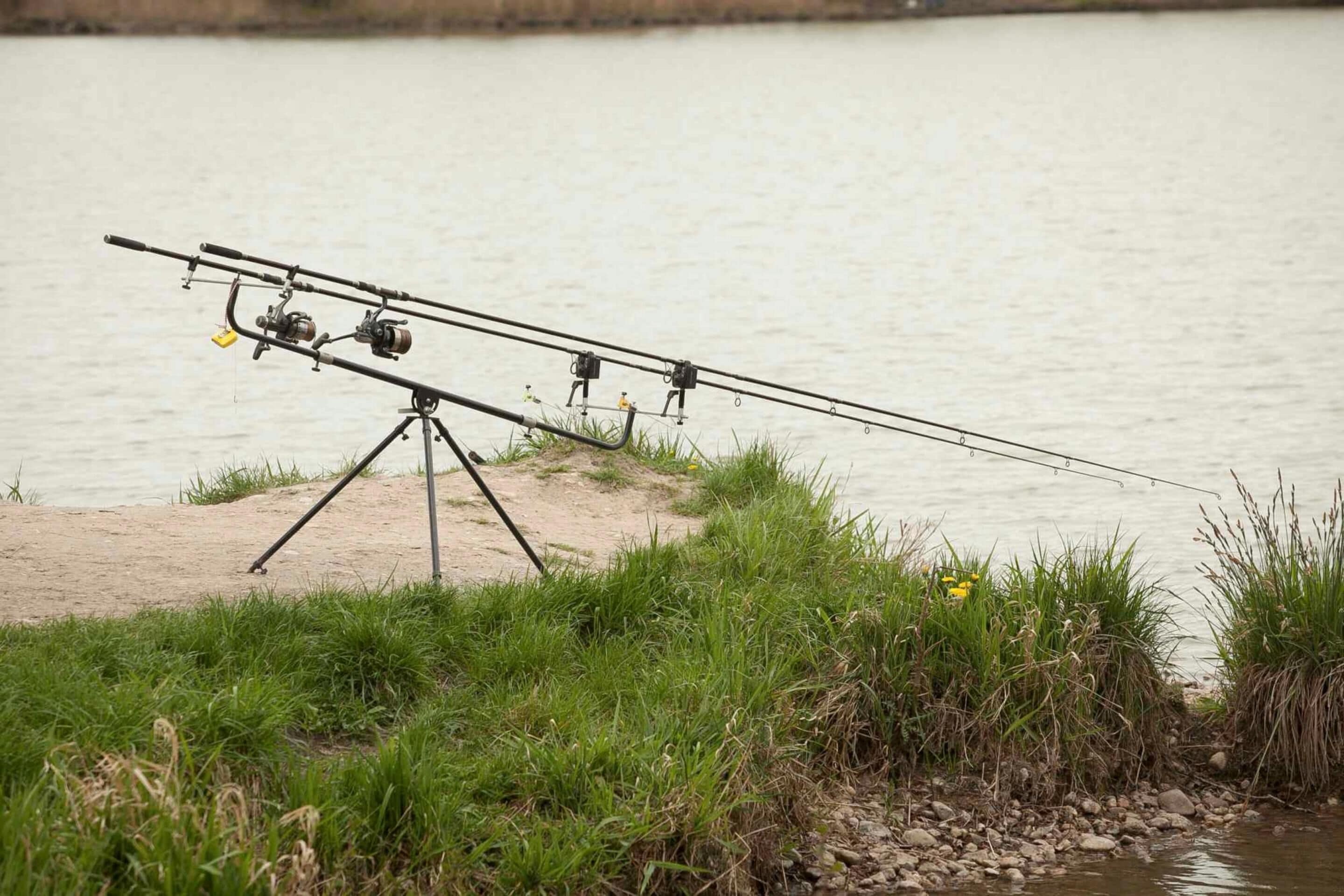 Vara de pesca montada em tripé à beira do rio.
