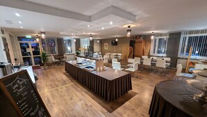 Um restaurante moderno com balcão central, cadeiras brancas e piso de madeira.