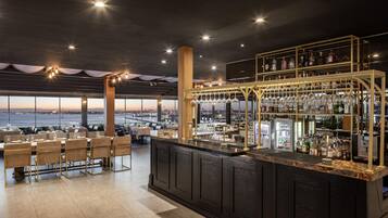 Um bar com vista para o horizonte da cidade e para a orla marítima.