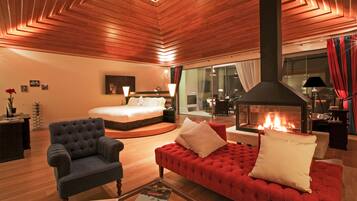 Uma sala de estar moderna com lareira, um sofá, uma poltrona e uma cama.