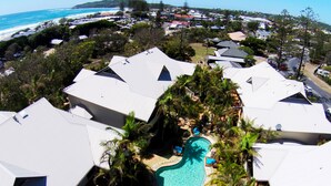 Bairro residencial com piscina, rodeado de casas e vegetação exuberante.