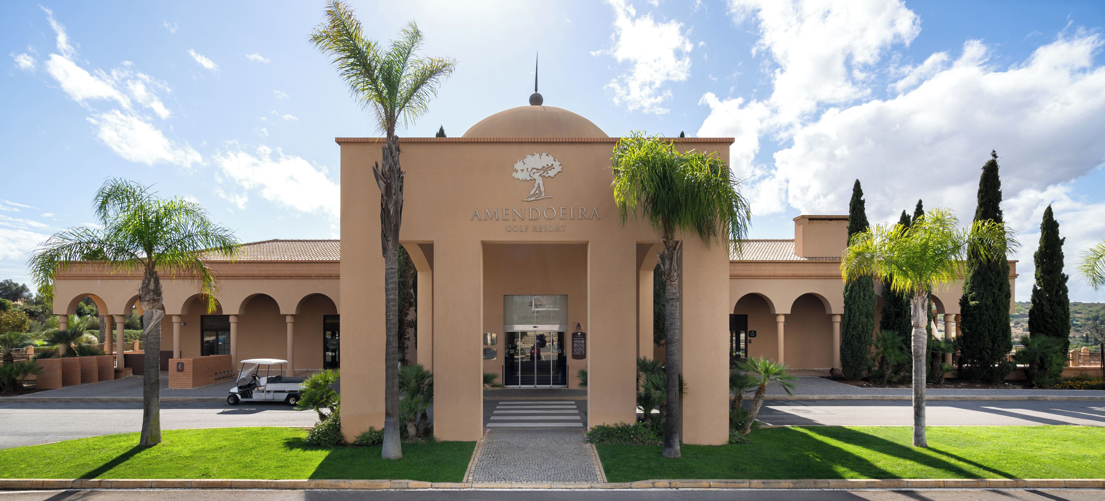 Um edifício com cúpula e arcos, com a identificação 'AMENDOEIRA GOLF RESORT'.