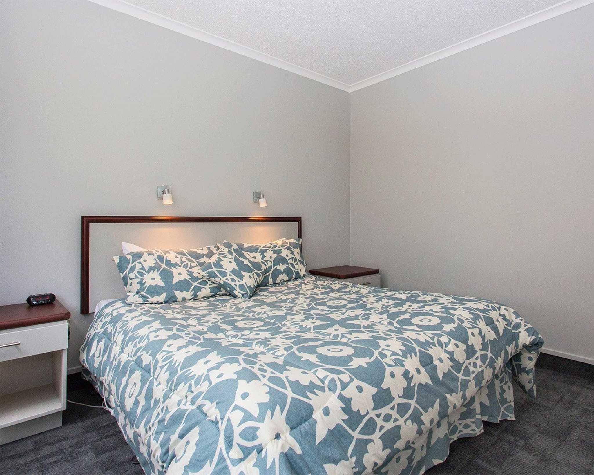 Quarto com uma cama, duas mesas de cabeceira e um criado-mudo.