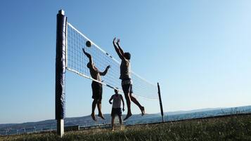 Jogo de voleibol de praia com jogadores a saltar sobre a rede.