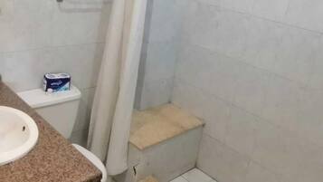 Uma casa de banho pequena com sanita, lavatório e zona de duche.