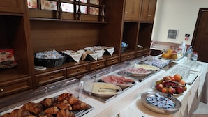 Buffet com diversas opções de comida, incluindo doces, carnes, queijos e frutas.