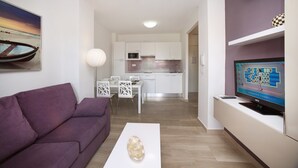Uma sala de estar moderna com um sofá roxo, uma mesa de centro branca e uma TV de tela plana.