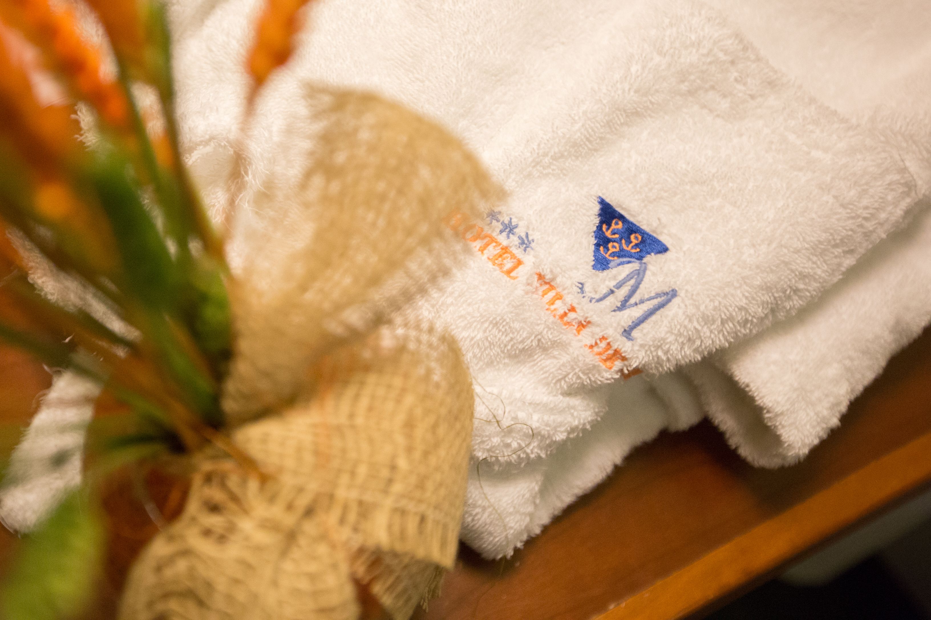 Uma toalha branca com bordado e um logotipo sobre uma superfície de madeira.