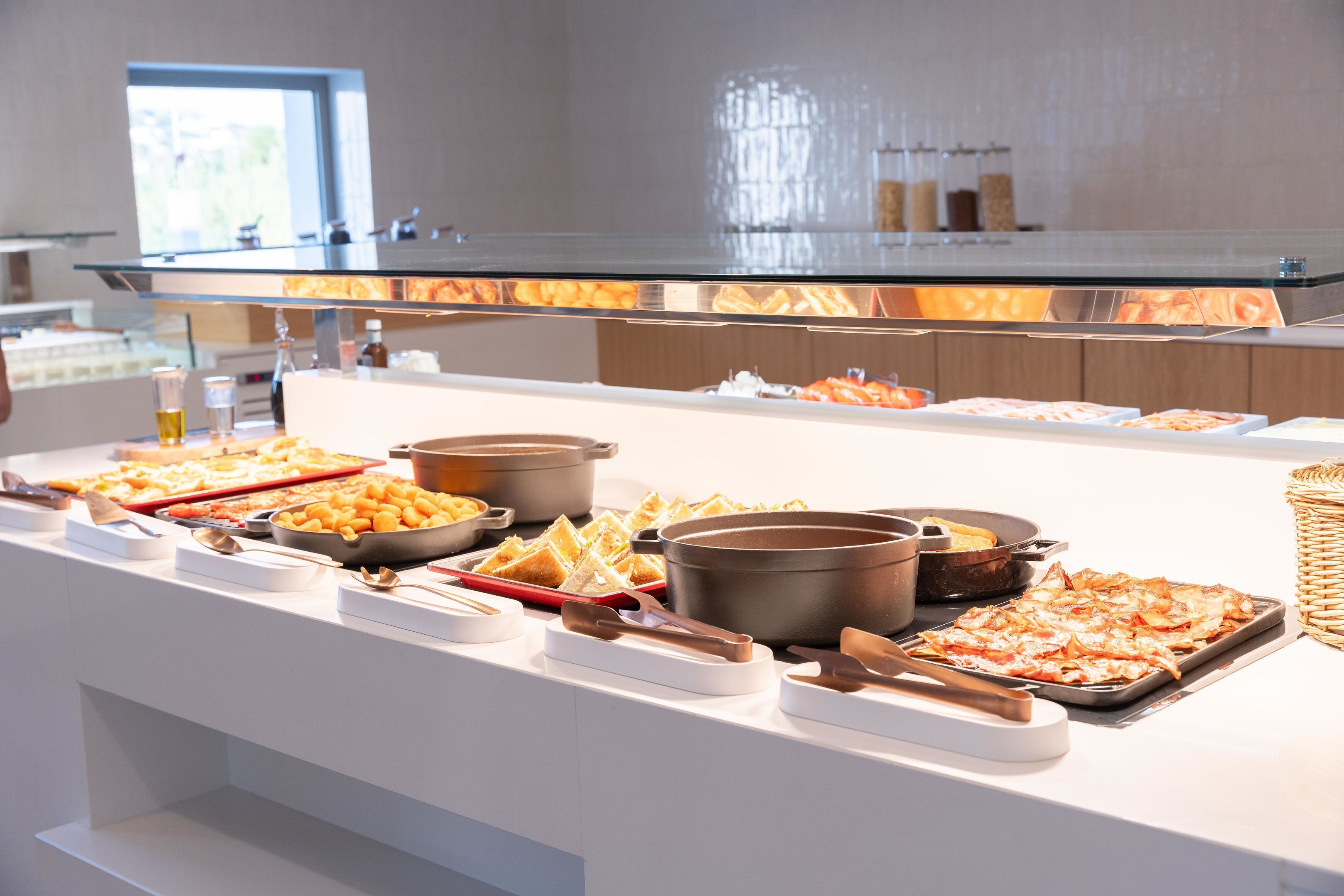 Buffet com diversos alimentos e utensílios de cozinha.