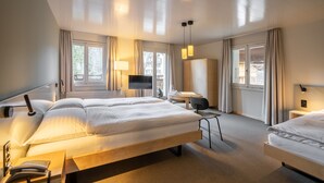 Quarto de hotel com duas camas, uma escrivaninha, uma televisão e um guarda-roupa.