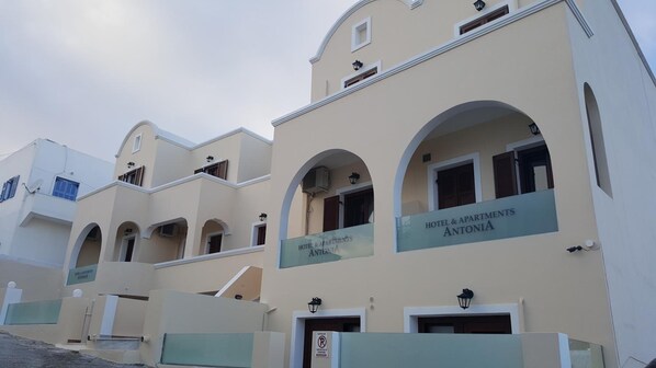 Uma fileira de edifícios com janelas em arco e um letreiro para Hotel & Apartments Antonia.