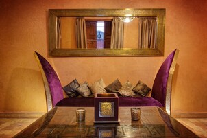 Um quarto com um sofá, uma mesa com uma caixa decorativa e um espelho na parede.