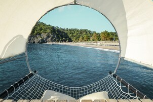 Na praia, espreguiçadeiras, prática de vela 