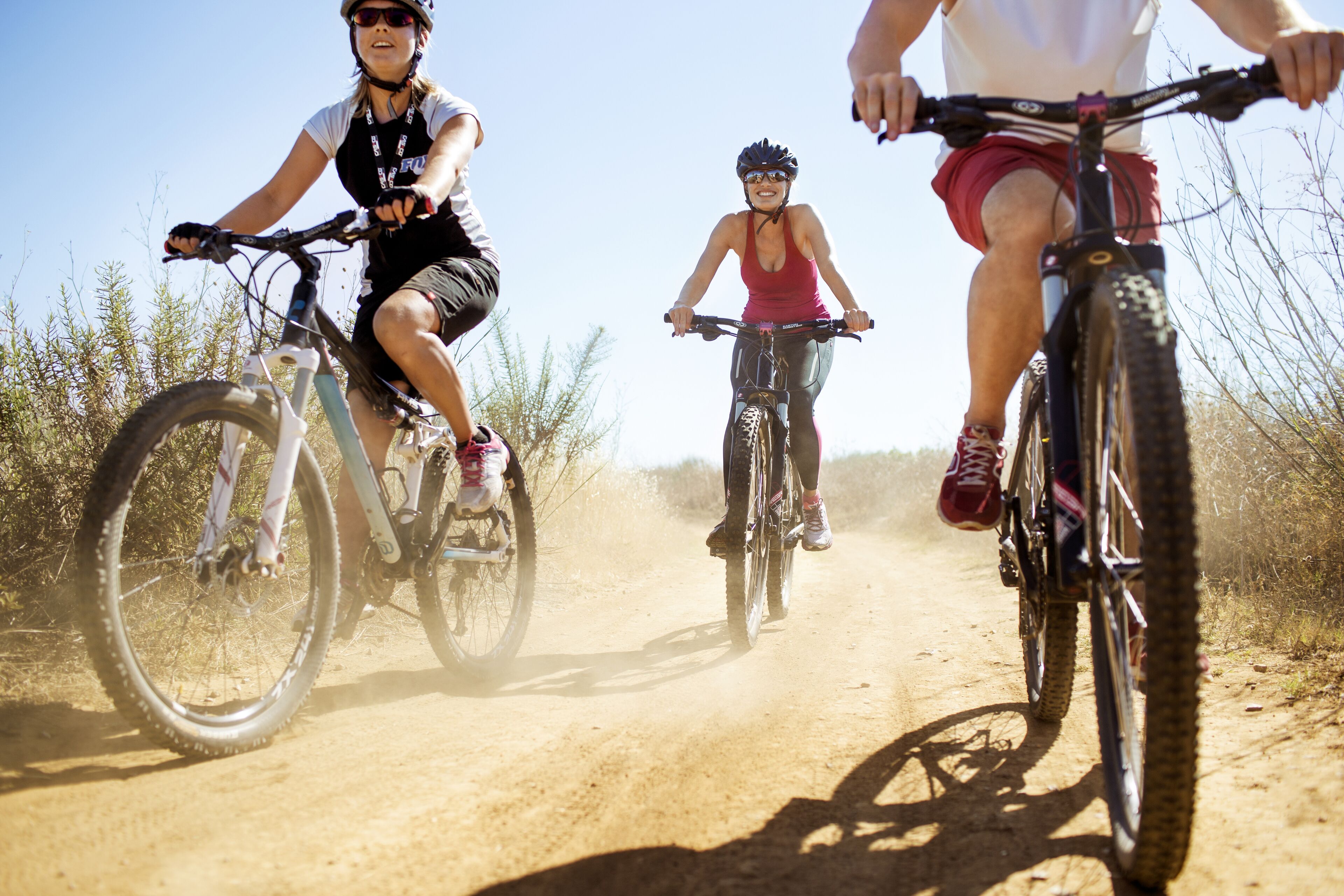 Três ciclistas em um caminho de terra.