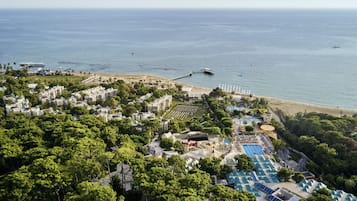 Vista aérea de um resort costeiro com vários edifícios, uma praia e área de piscina.