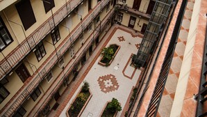 Um edifício com vários andares, varandas, um pátio com azulejos decorativos e vasos com plantas.