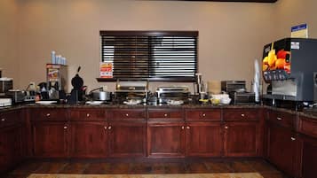 Cozinha com bancadas de granito, armários de madeira, máquina de café e dispensador de frutas.