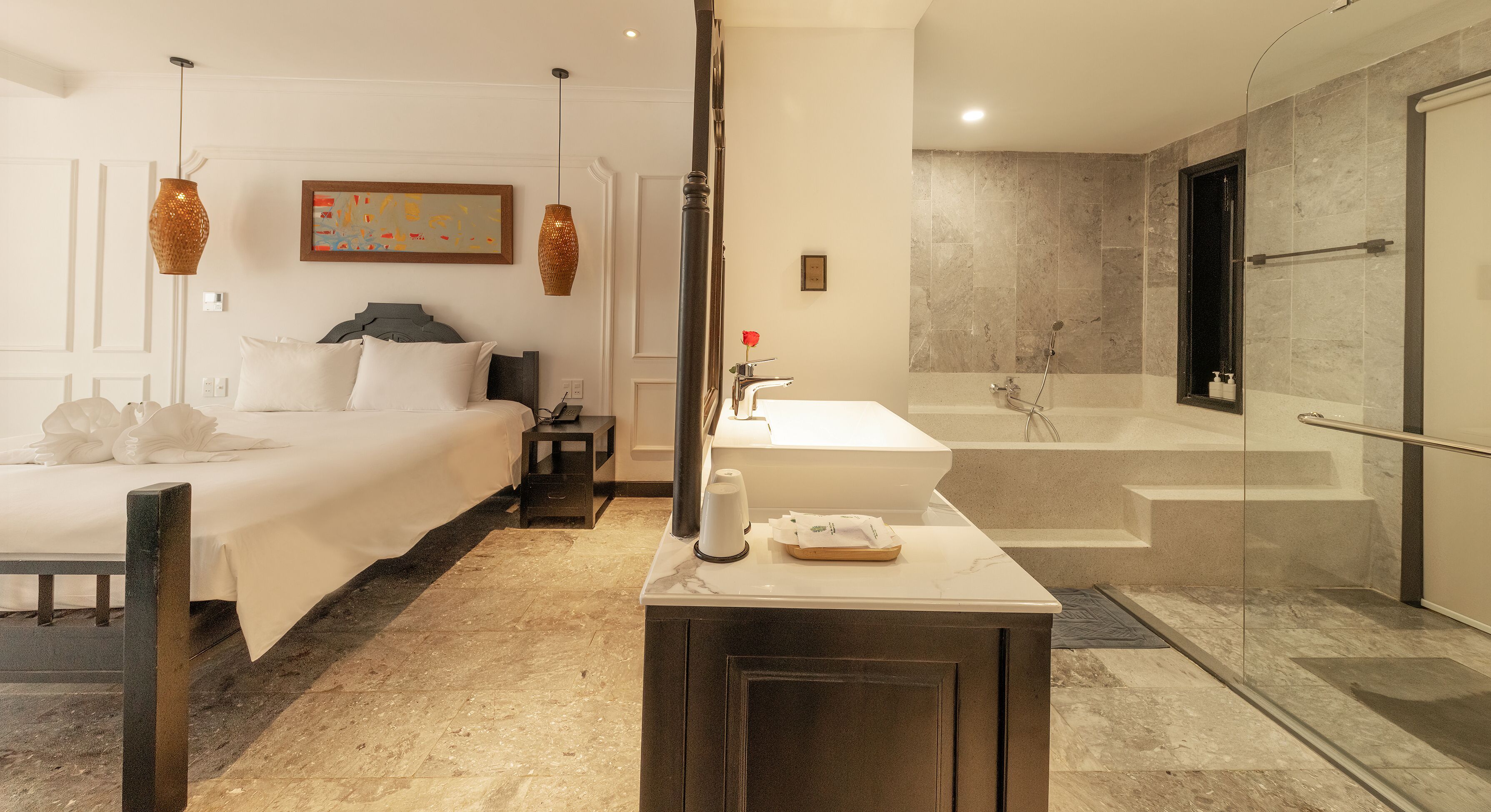 Quarto de hotel com cama, mesa de cabeceira e banheiro com banheira e chuveiro.