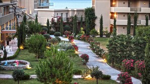 Um jardim bem cuidado com um caminho serpenteante, sebes aparadas e diversas plantas floridas.