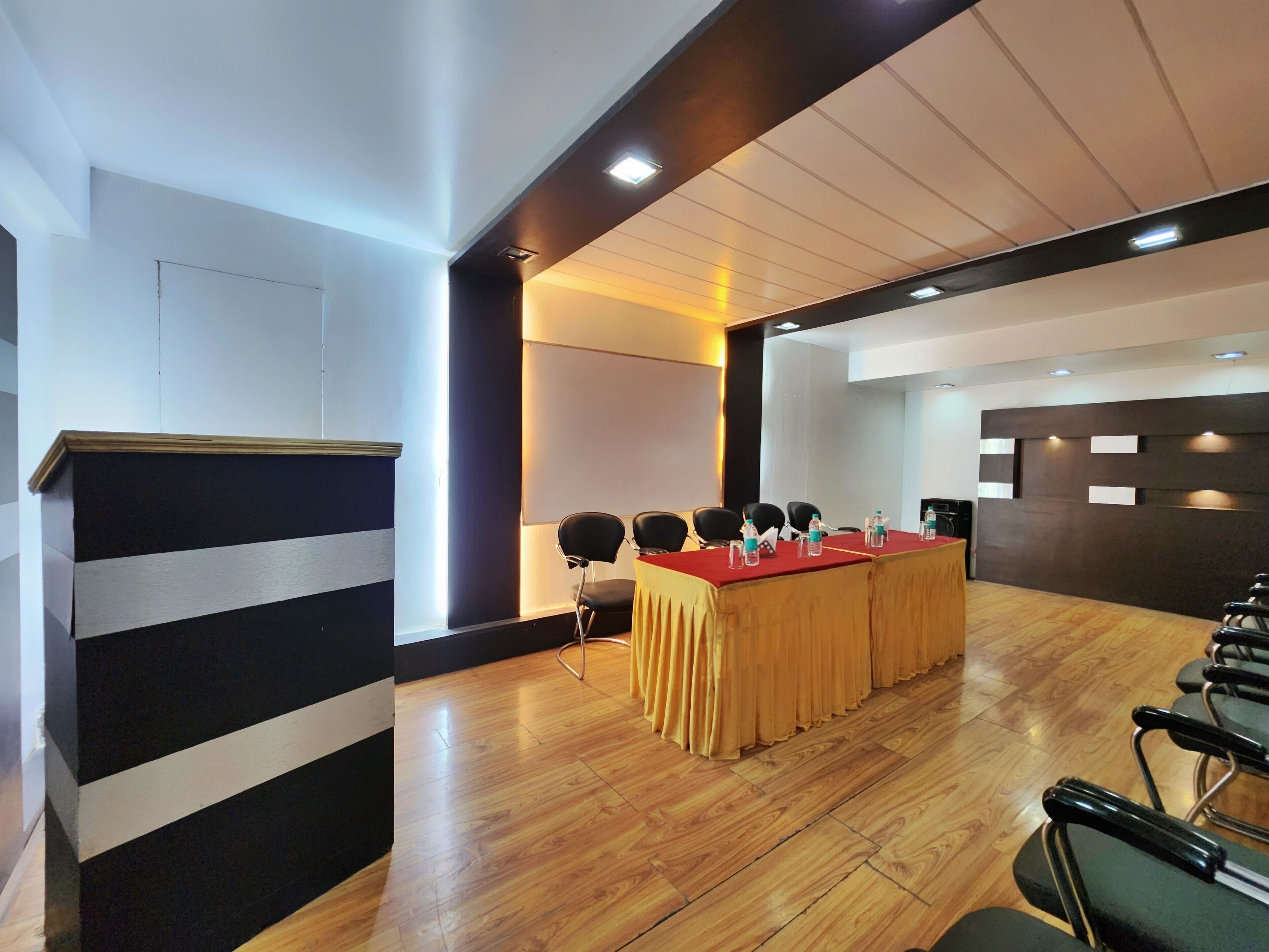 Uma sala de conferências com uma mesa comprida, cadeiras e um pódio.