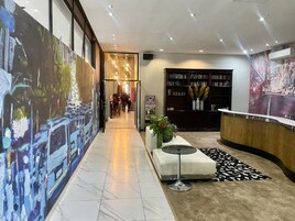 Um hall moderno com piso de mármore, um balcão de recepção, uma estante de livros e um grande quadro abstrato na parede.