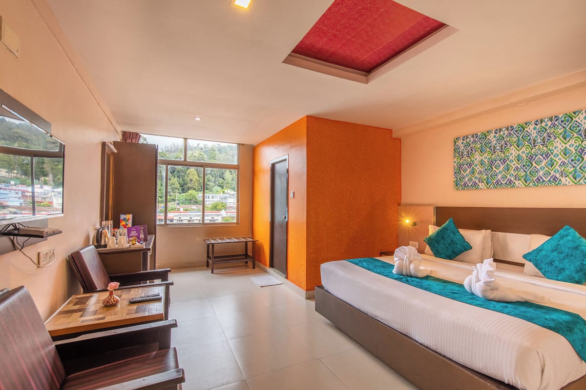 Quarto de hotel com uma cama grande, uma escrivaninha com cadeira e janela com vista para o exterior.