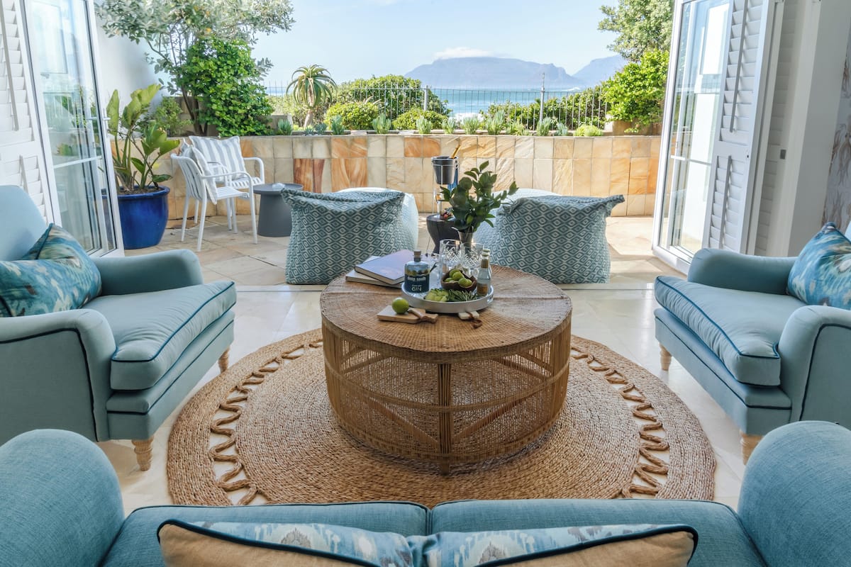 Uma sala de estar moderna com uma mesa de centro de vime redonda, dois sofás e vista para o oceano.