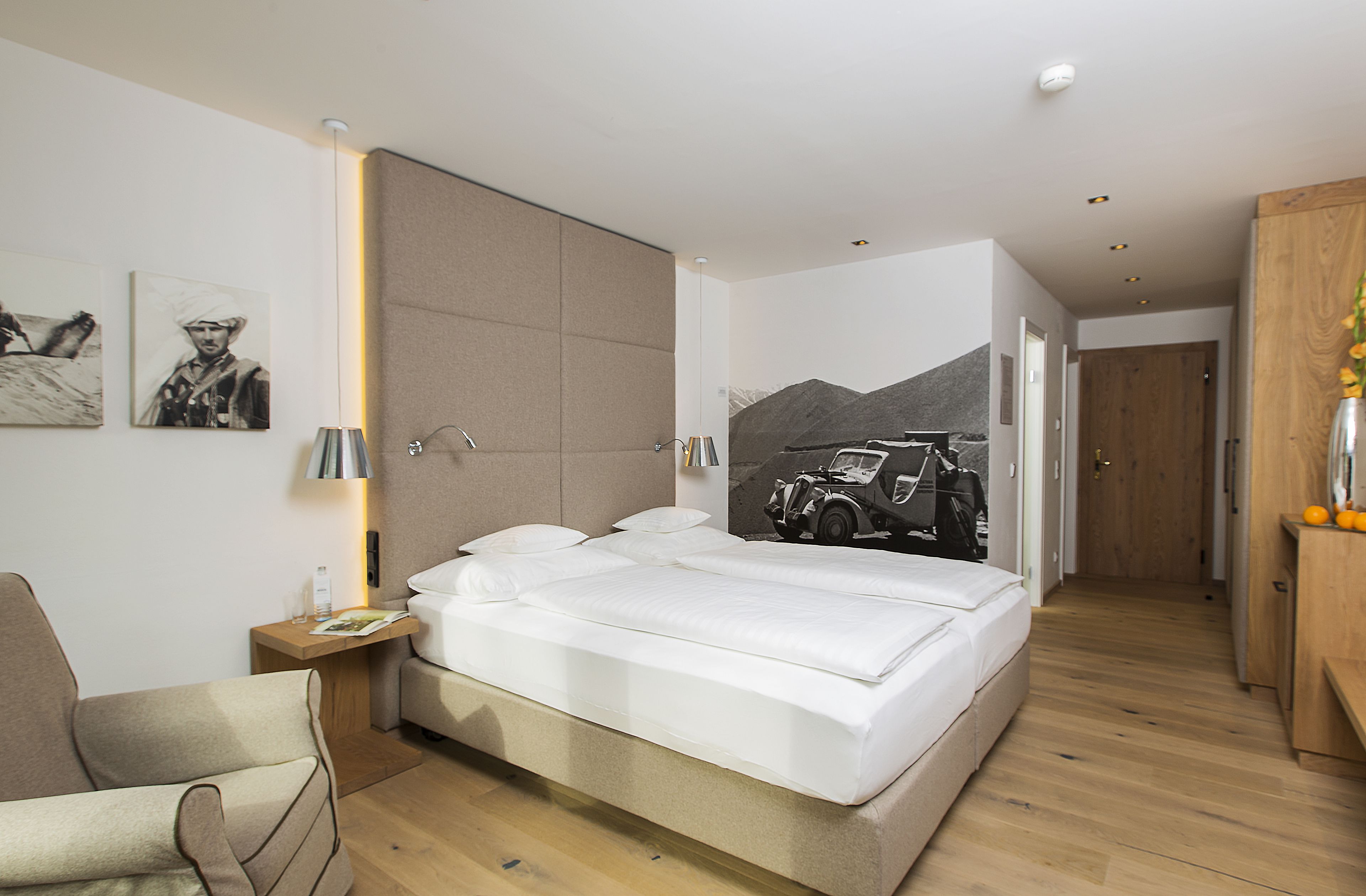 Um quarto moderno com uma cama grande, uma mesa de cabeceira, uma cadeira e uma luminária na parede.