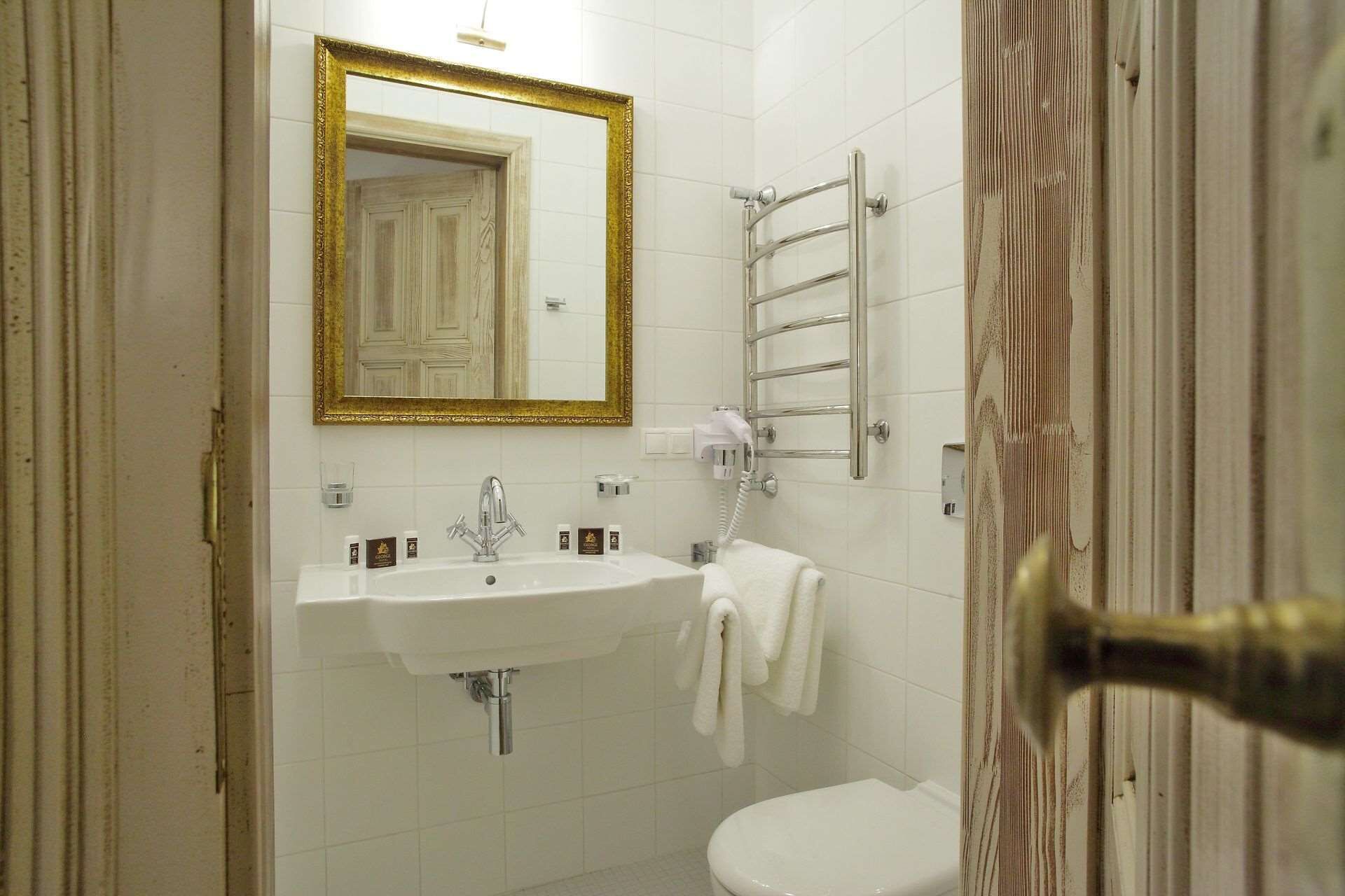 Casa de banho com lavatório, espelho, porta-toalhas e sanita.
