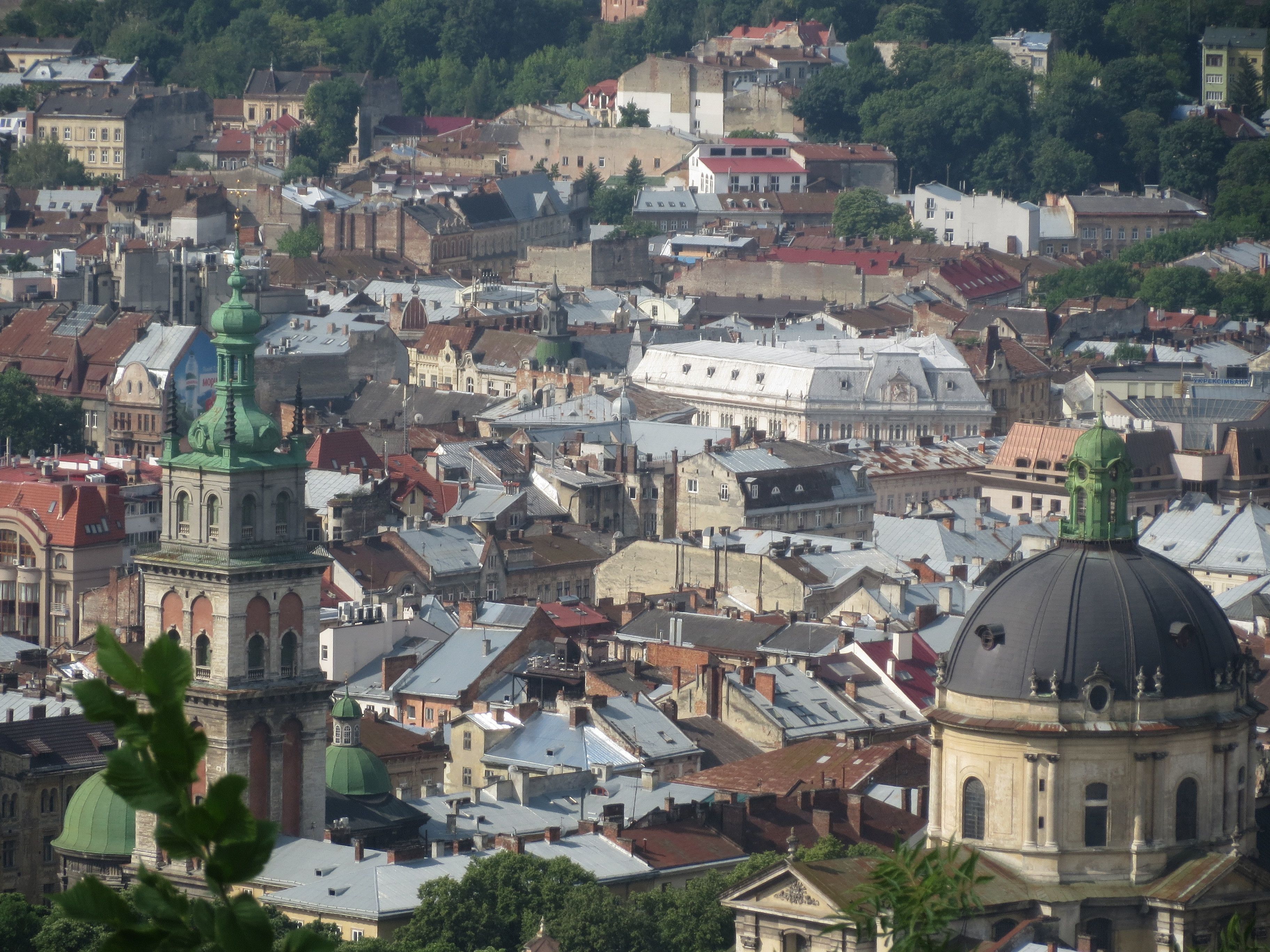 Uma área urbana densamente povoada com edifícios históricos, incluindo uma igreja notável com cúpula verde e uma grande estrutura em forma de cúpula.