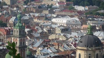 Uma área urbana densamente povoada com edifícios históricos, incluindo uma igreja notável com cúpula verde e uma grande estrutura em forma de cúpula.