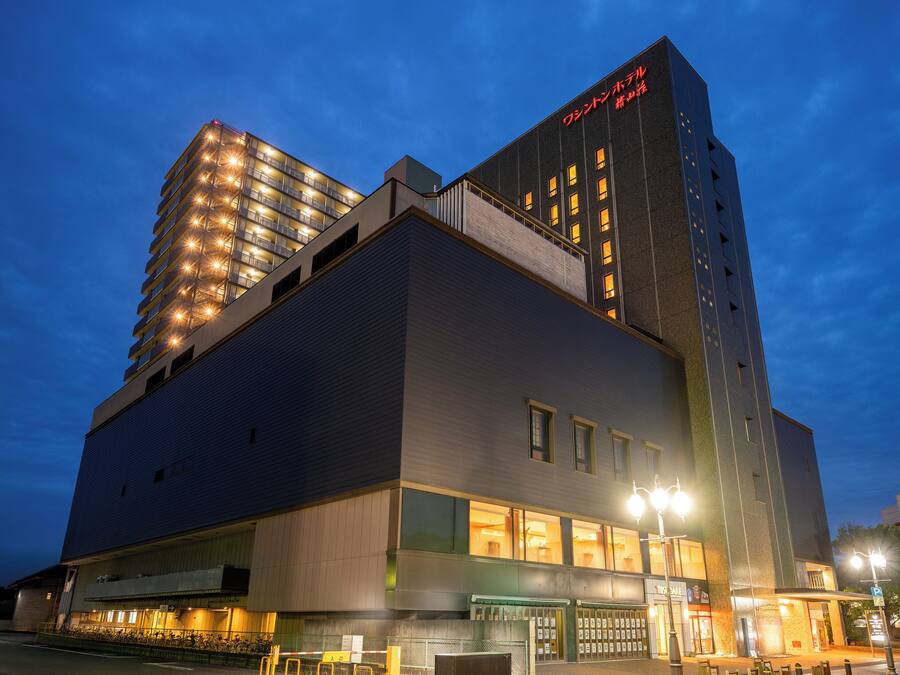 Hotel com vários andares, janelas iluminadas e uma placa bem visível.