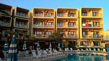 Um hotel com várias varandas, piscina e espreguiçadeiras.