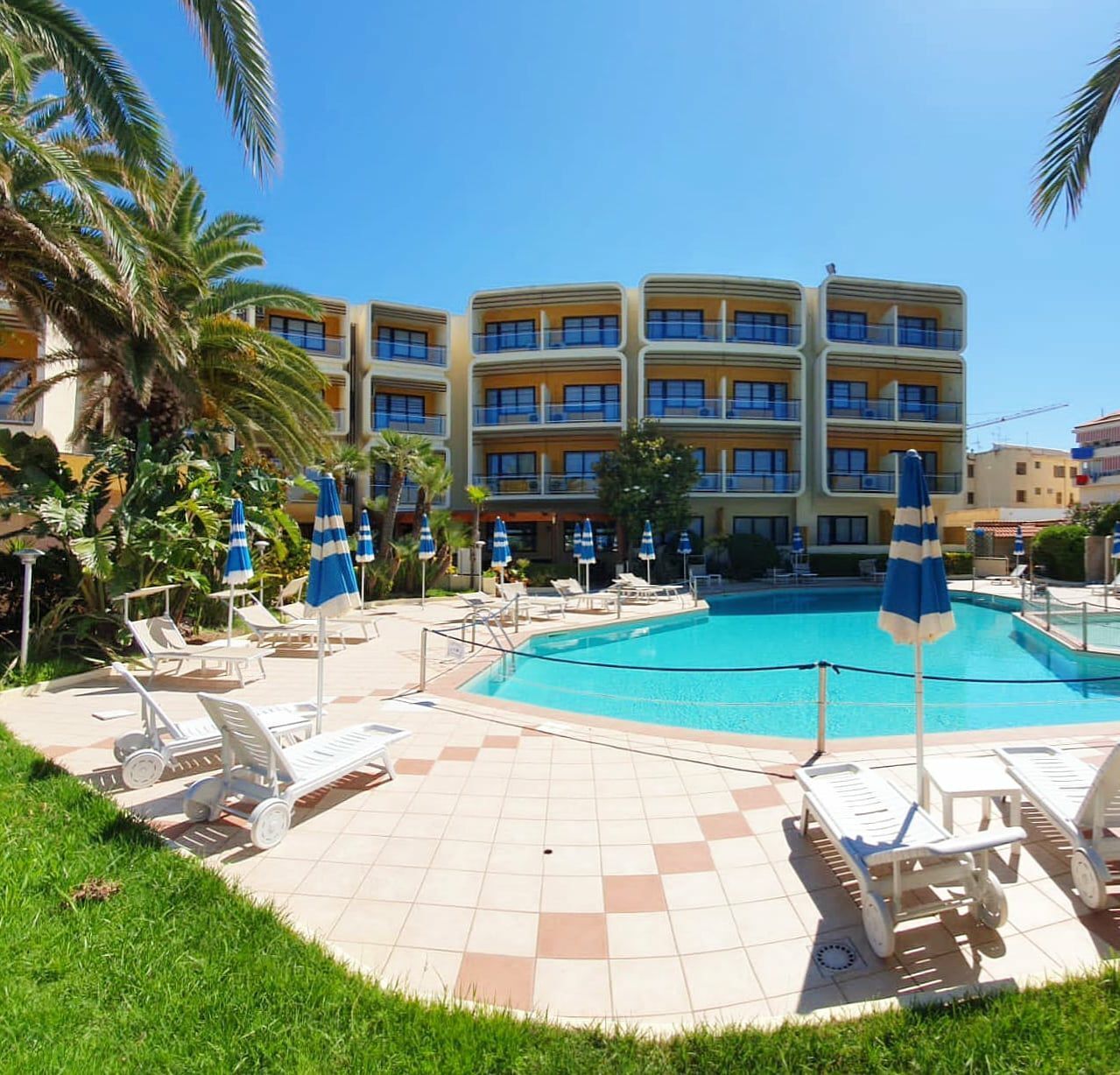 Um hotel com piscina, espreguiçadeiras e guarda-sóis.
