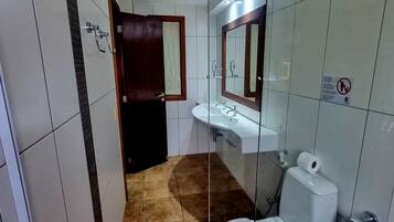 Um banheiro moderno com pia branca, espelho e vaso sanitário.