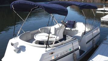 Um barco a motor branco atracado num cais, com área de estar coberta e uma pequena mesa.