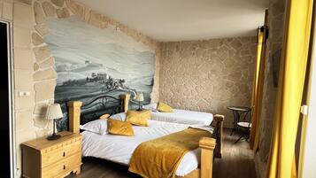 Quarto com mural de parede de pedra, móveis de madeira e cama com manta amarela.