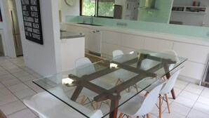 Uma cozinha moderna com uma mesa de jantar de vidro e cadeiras brancas.
