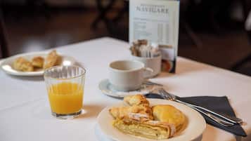 Um cenário de café da manhã com croissants, um copo de suco de laranja e uma placa de menu.