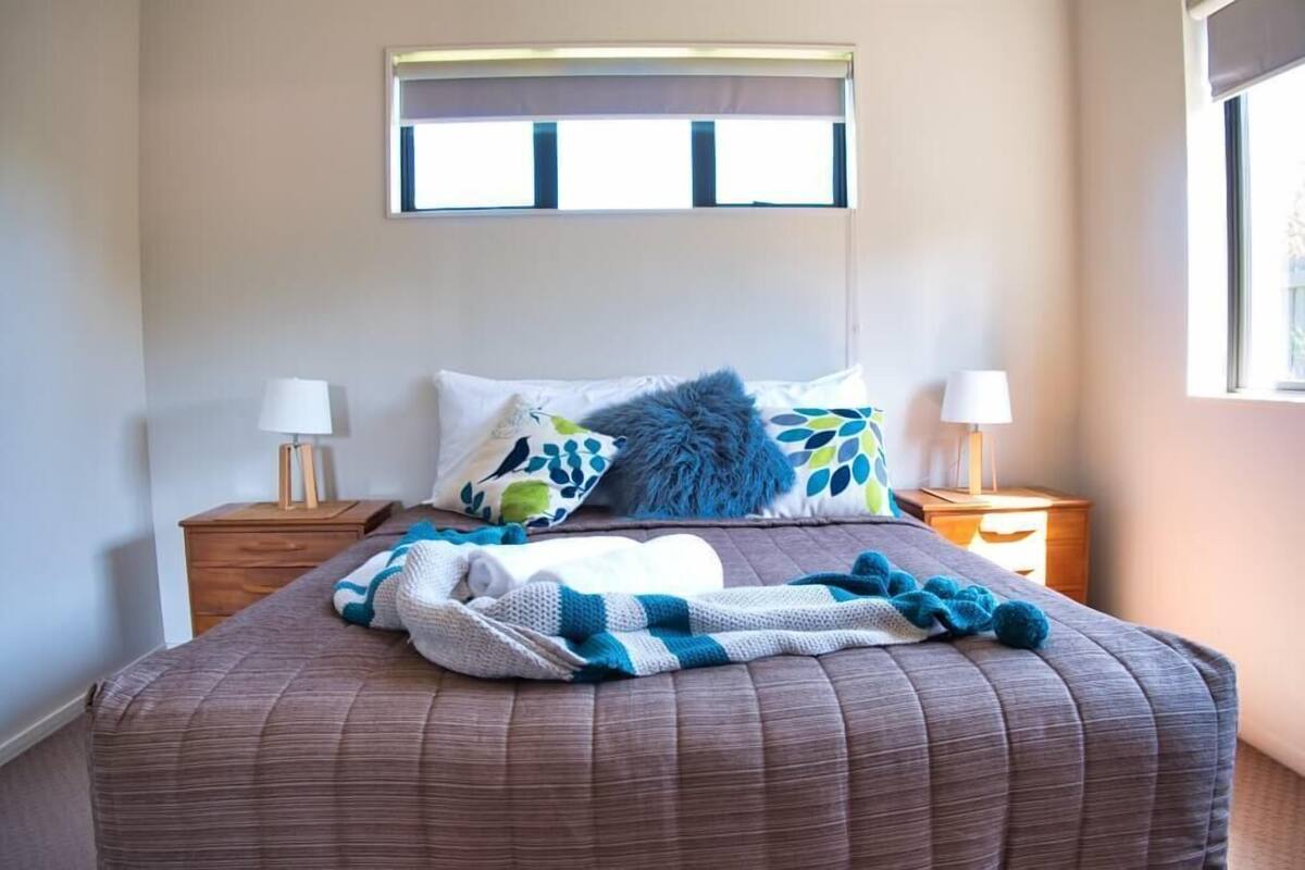 Quarto com cama, duas mesas de cabeceira e uma janela.