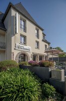 Um hotel com uma placa indicando 'HOTEL La Résidence' e uma área de estar coberta ao ar livre, com mesas e guarda-sóis.