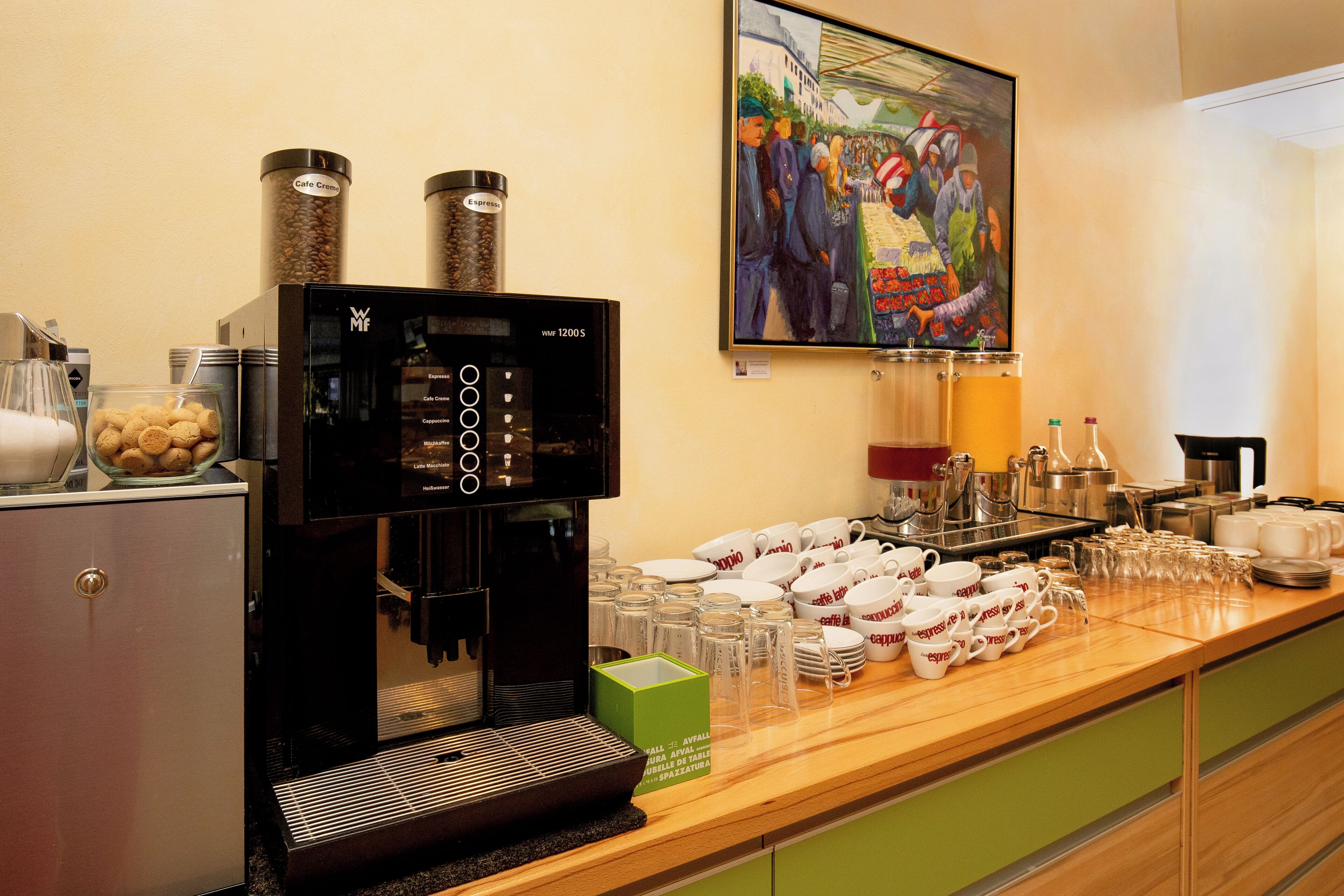 Um espaço com estação de café, máquina de café, chávenas e um quadro na parede.