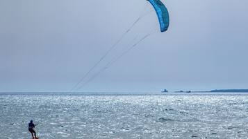Uma pessoa praticando windsurf em um mar calmo sob um céu claro.