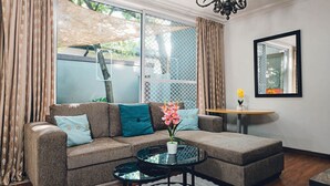Uma sala de estar com um sofá, uma mesa de centro e uma mesinha lateral.