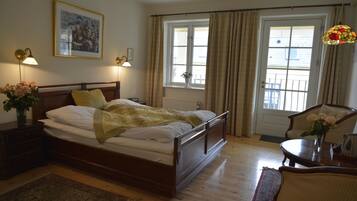 Quarto com cama de madeira, luminárias de cabeceira, mesa de cabeceira, janela com cortinas e vista para o exterior.