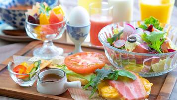 Bandeja de café da manhã com diversos alimentos, incluindo ovos, presunto, torradas e salada de frutas.