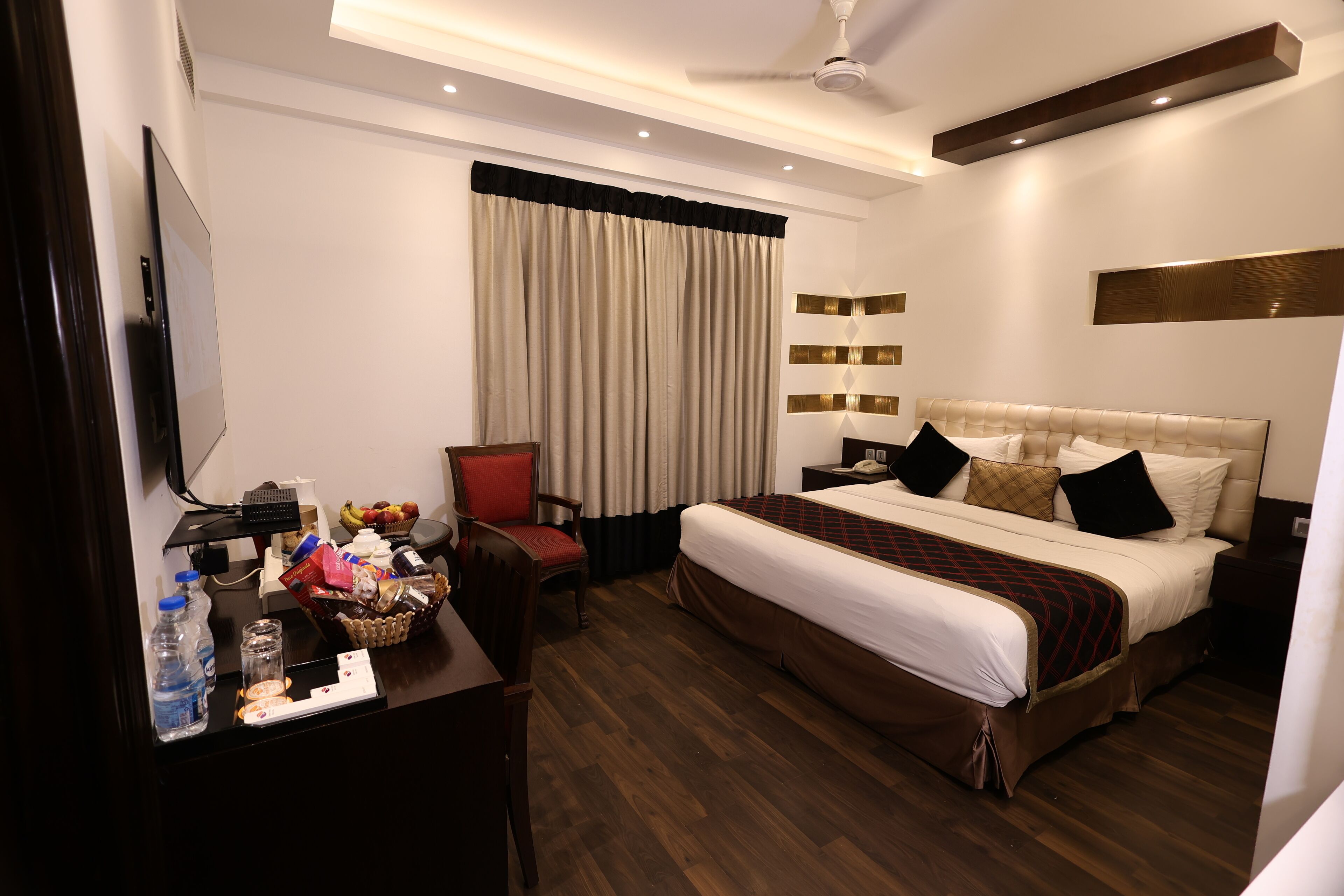 Quarto de hotel com cama, mesa de cabeceira, cadeira e escrivaninha com diversos objetos.