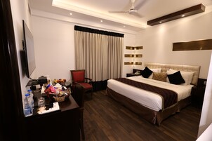 Quarto de hotel com cama, mesa de cabeceira, cadeira e escrivaninha com diversos objetos.